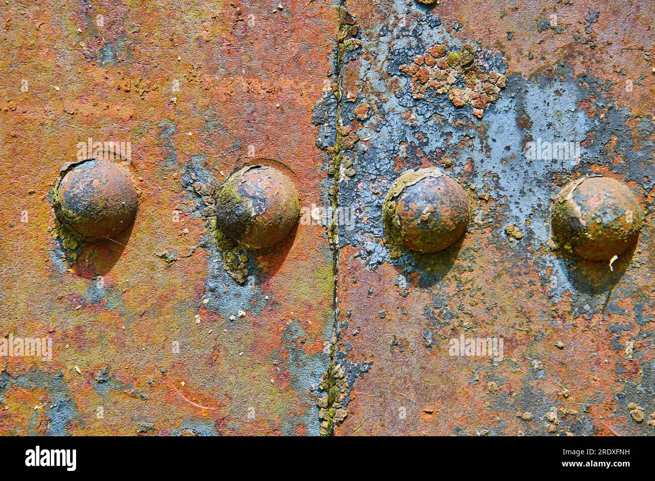 Four rivets split by crack on rusty decaying corroding iron metal ...