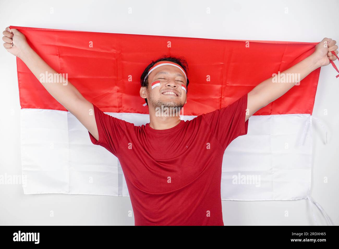Happy smiling Indonesian man holding Indonesia's flag to celebrate ...