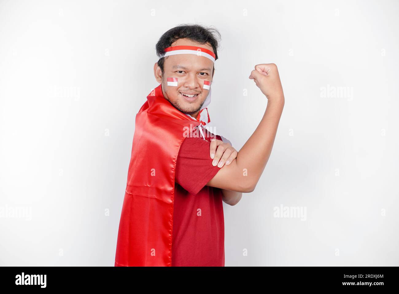 Excited Asian man wearing a red top, flag cape and headband, showing ...