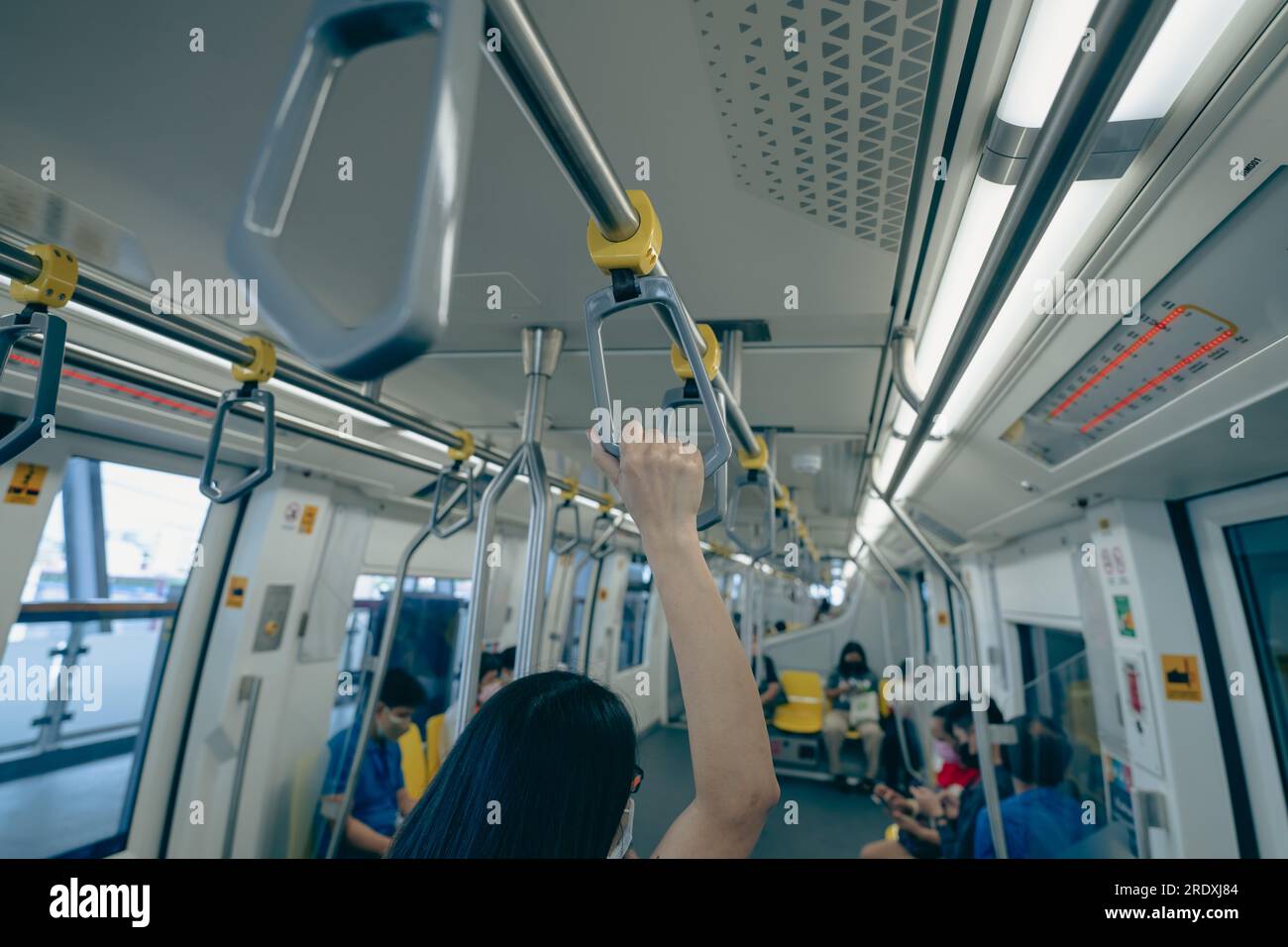 Woman hand firm grip safety handrail in elevated monorail train. Mass transit system in modern ...