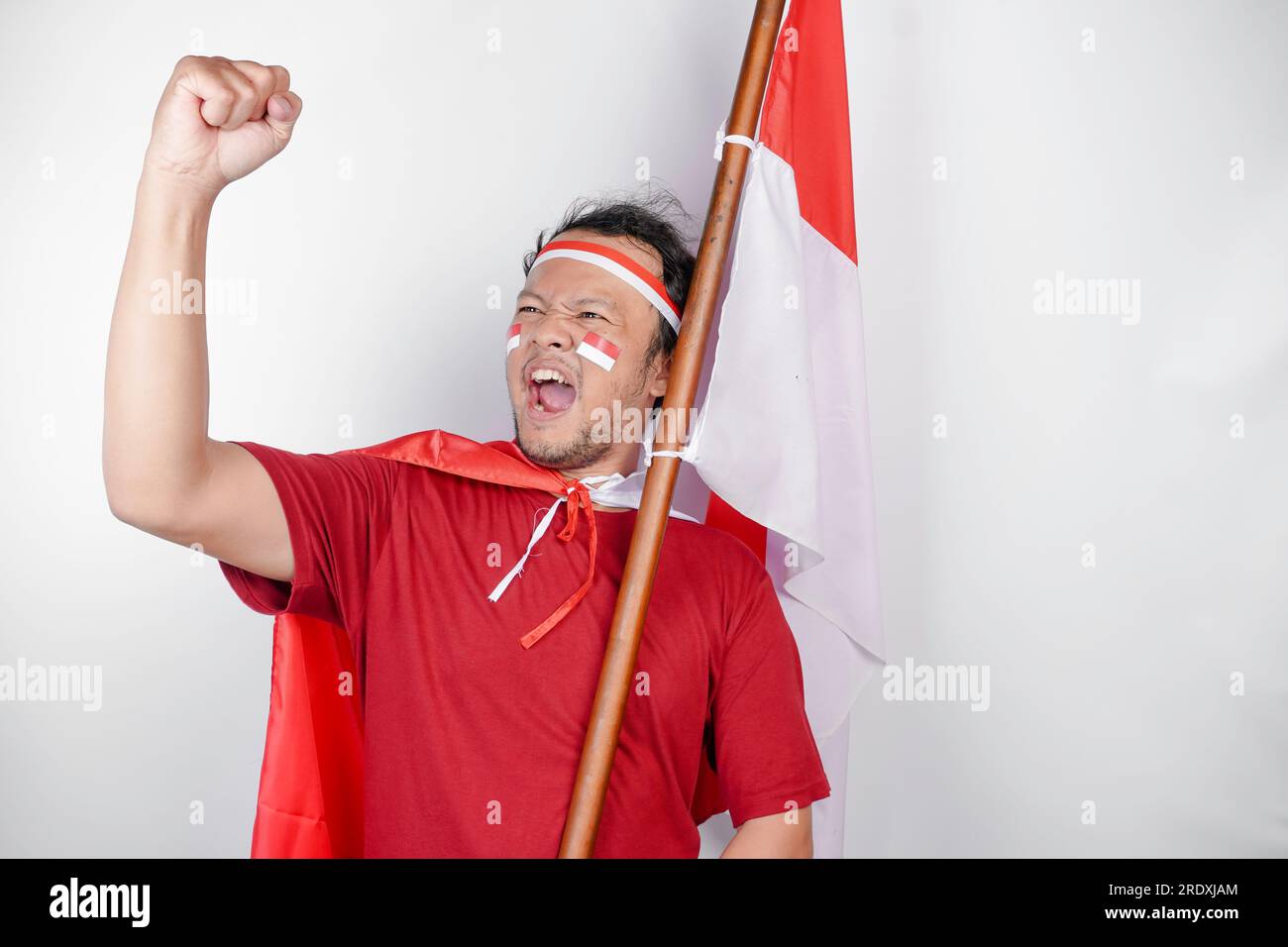 A young Asian man with a happy successful expression wearing red top ...