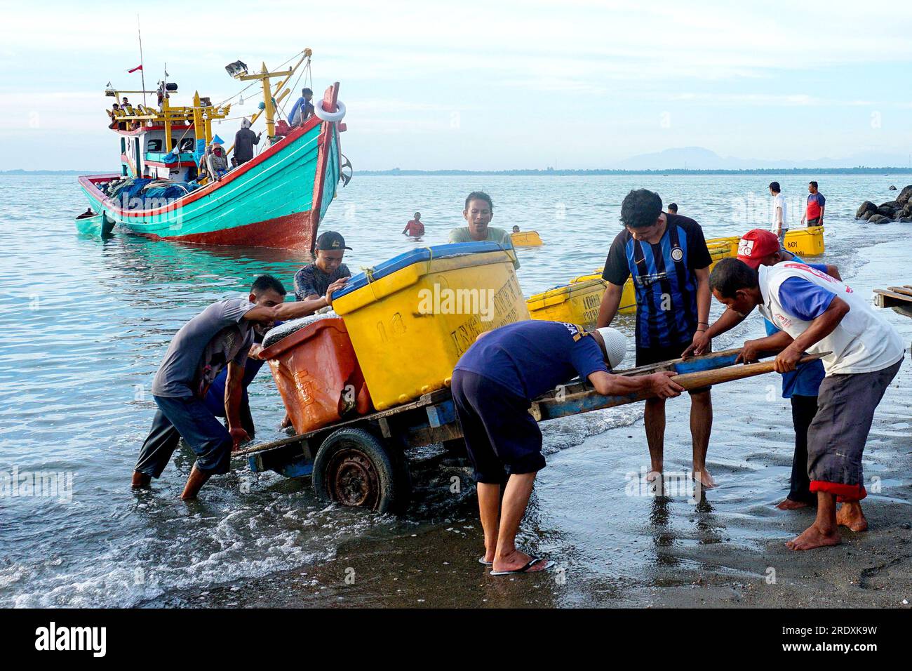 Lhokseumawe, Indonesia. 23rd July, 2023. People push fish containers on ...