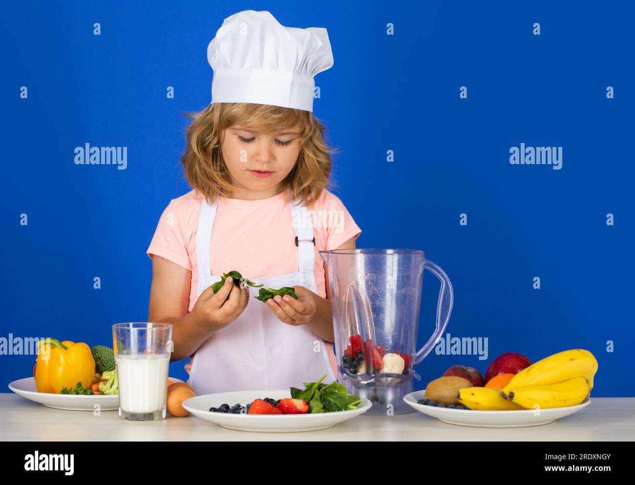 Kid boy in chef hat and apron cooking preparing meal. Little cook with ...