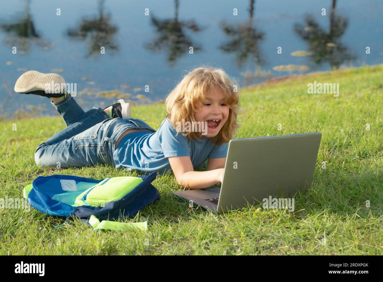 Outdoor online education with laptop. Kid lying on grass using laptop ...