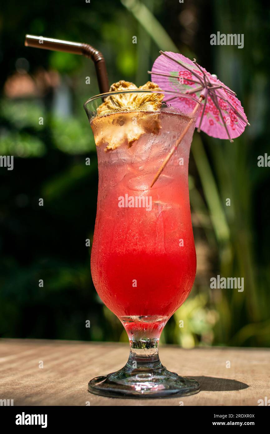 tropical sinagpore sling cocktail in tall glass at outdoors garden bar ...