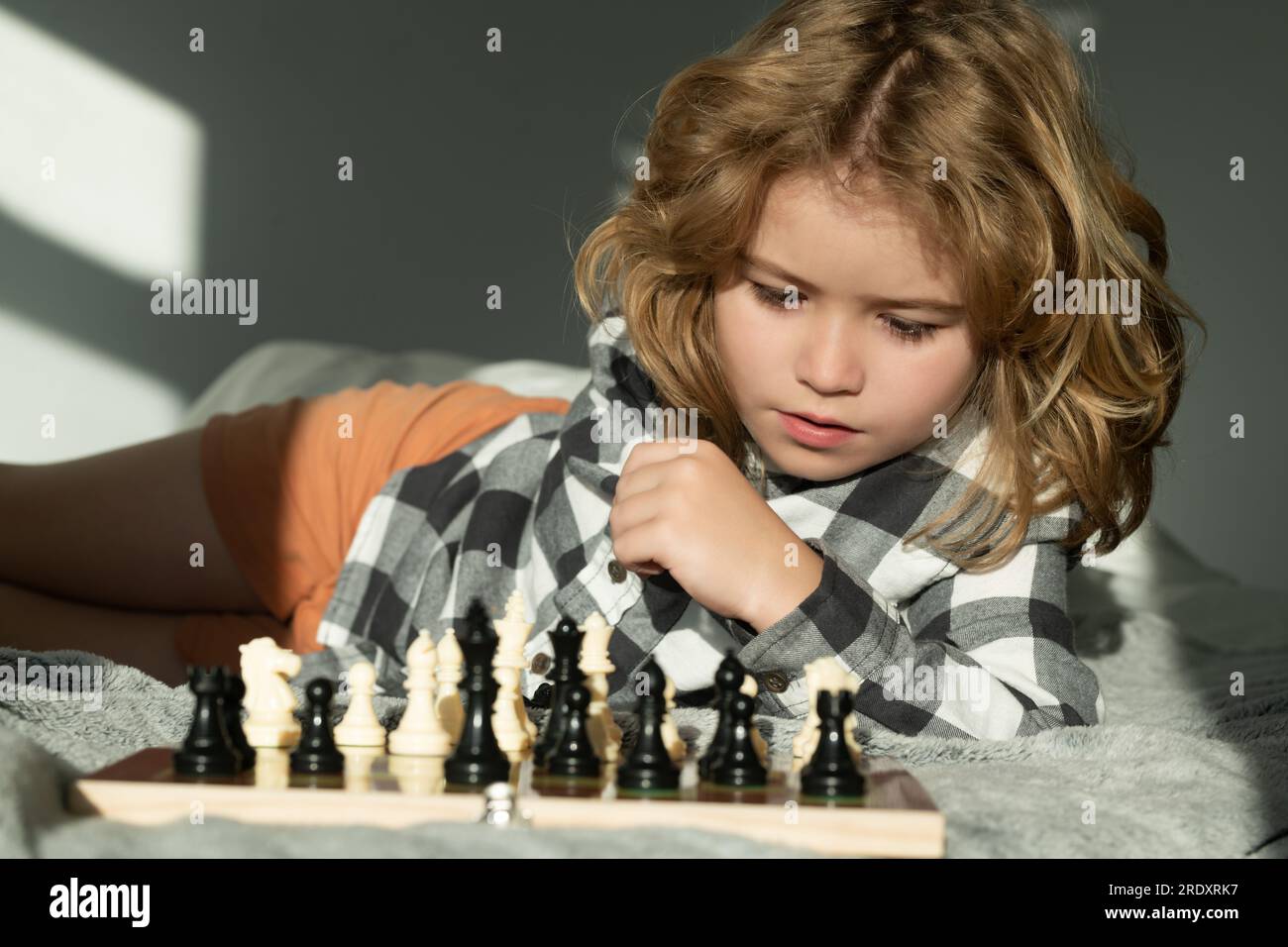Cute child playing chess at home. Portrait of clever kid with ...