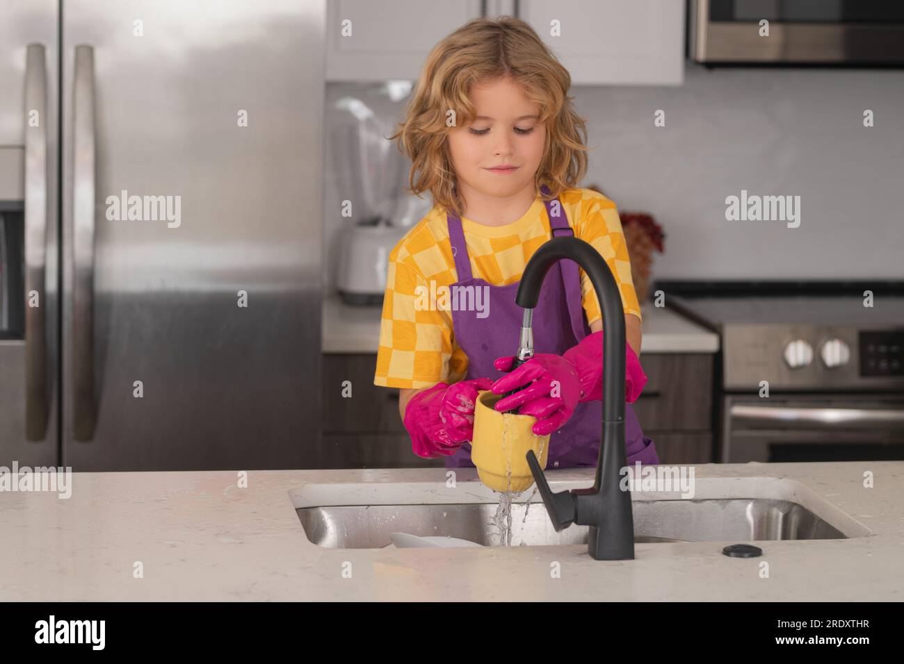 Cute kid help in washing dishes at kitchen. Kid cleaning of kithen help ...