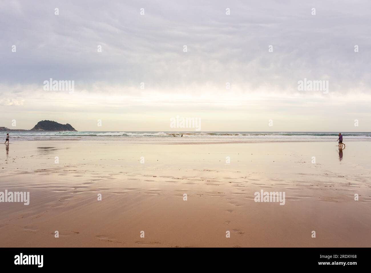 Walking people on wide beach of Biscayne bay, Spain. Surf beach with ...