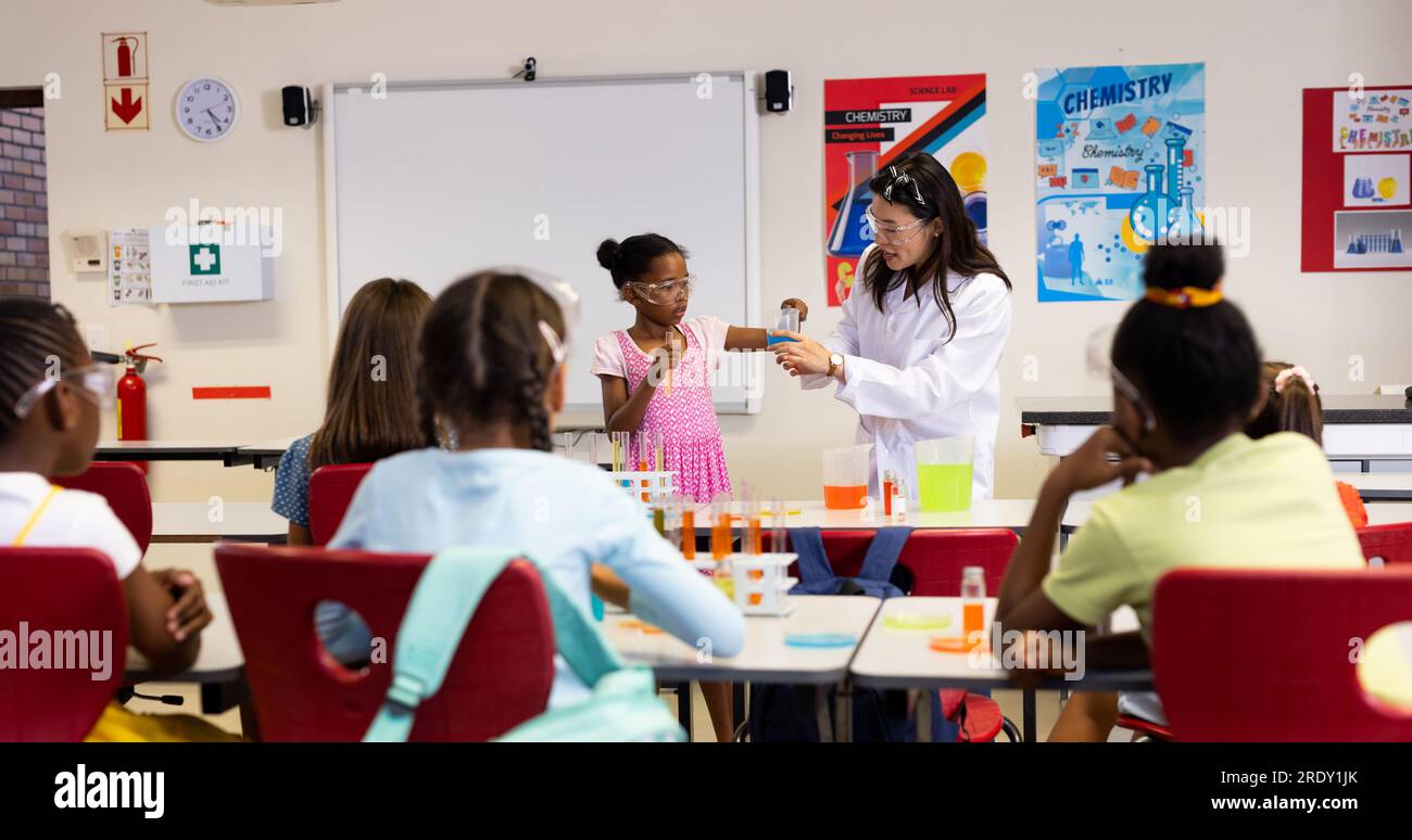 Diverse female teacher and schoolgirls with chemistry items and liquids ...