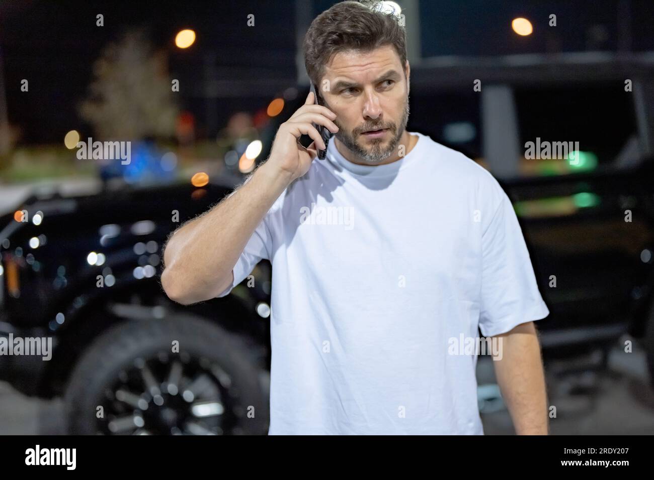 Gangster, criminal concept. Angry man near car on night urban street ...