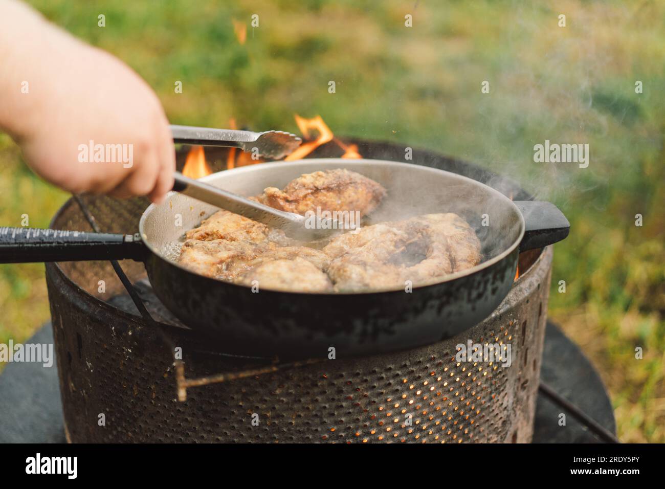 Man cooking fish on fire in nature, camping outdoors Stock Photo - Alamy