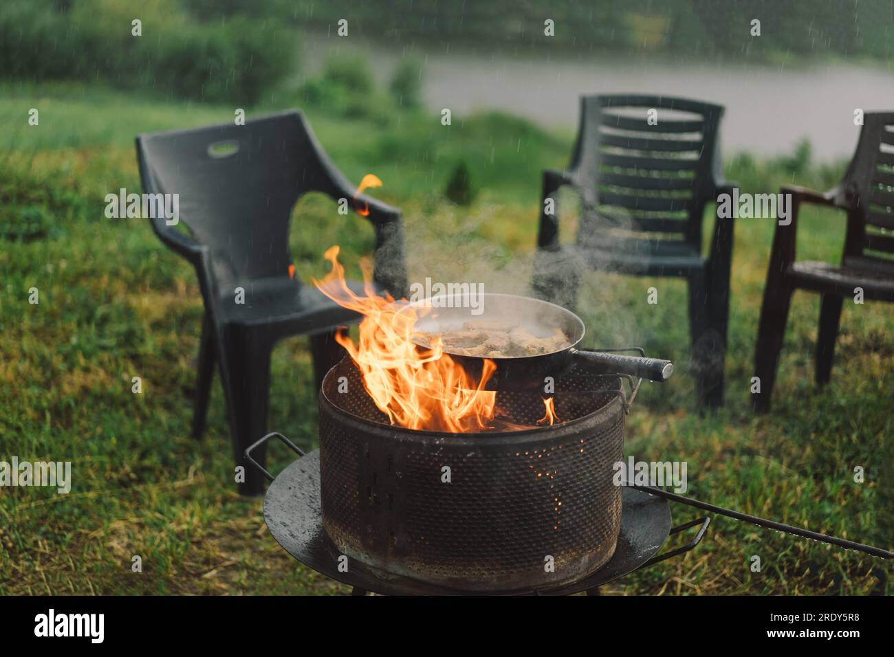 Man cooking fish on fire in nature, camping outdoors Stock Photo - Alamy