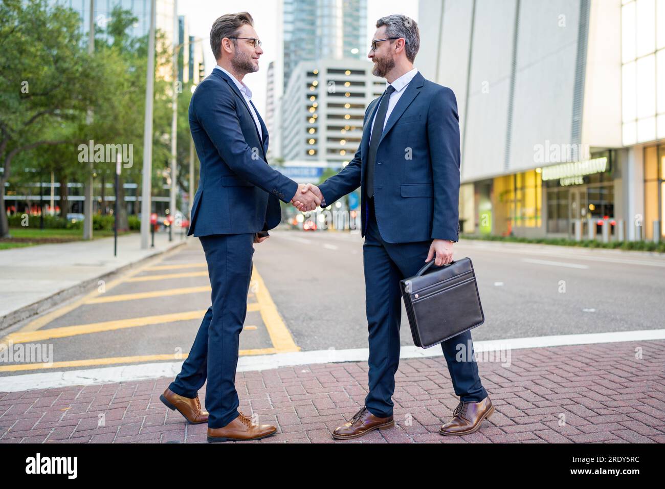 Businessmen in suit shaking hands outdoors. Handshake between two ...