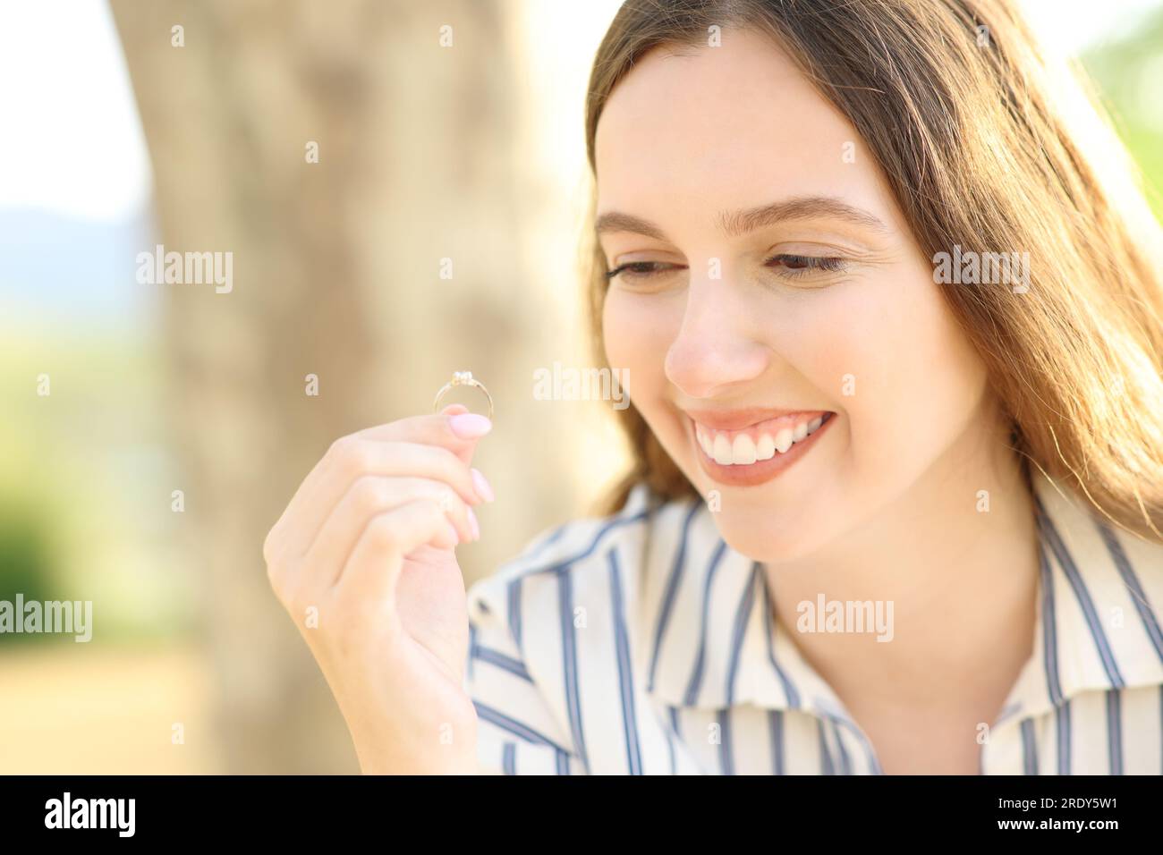 Happy fiancee enjoying looking at engagement ring in nature Stock Photo ...