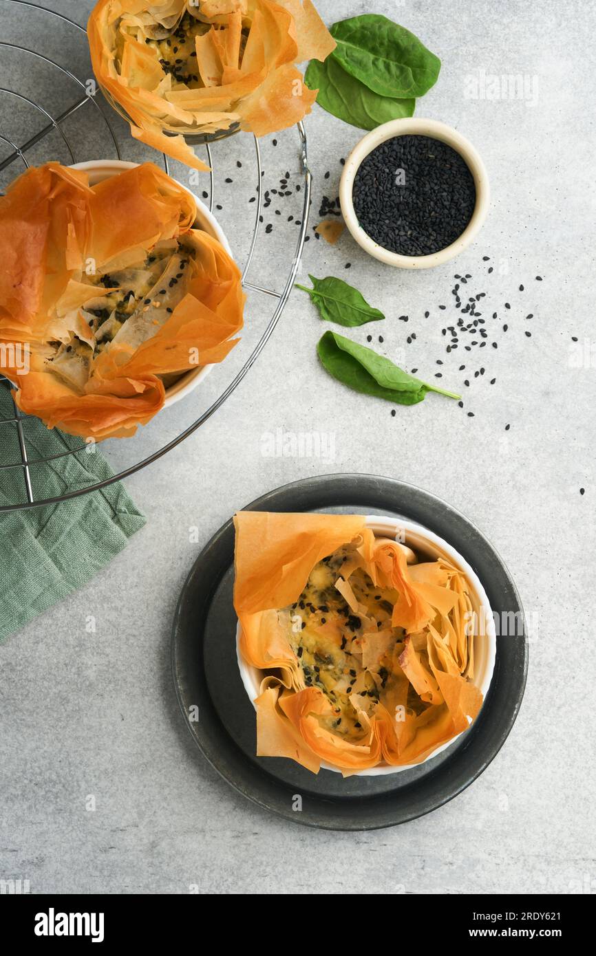 Filo pies with soft feta cheese and spinach in ceramic molds on old ...