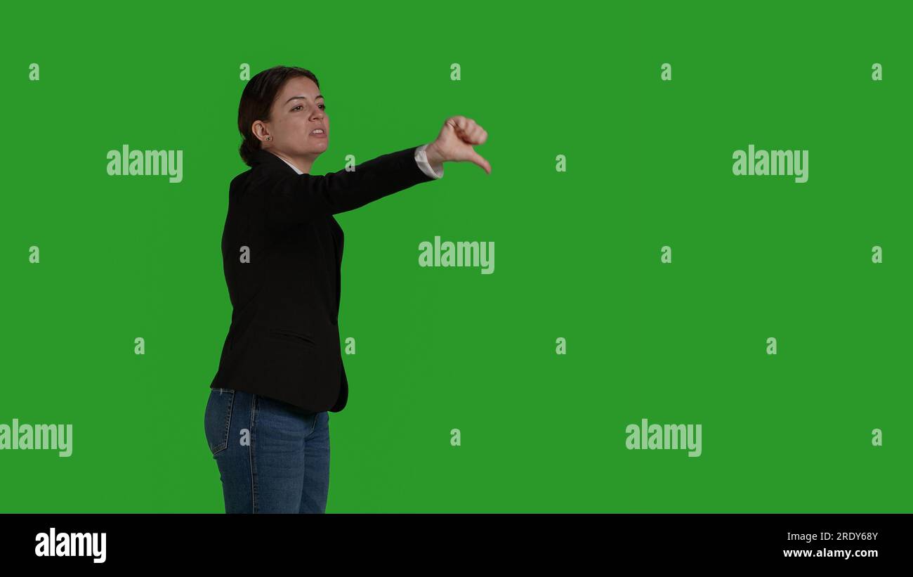 Side view of corporate employee giving thumbs down symbol in studio ...