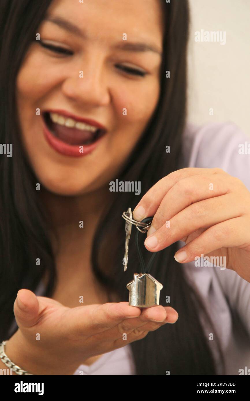 Latin adult woman shows the keys to her new home on a house-shaped ...