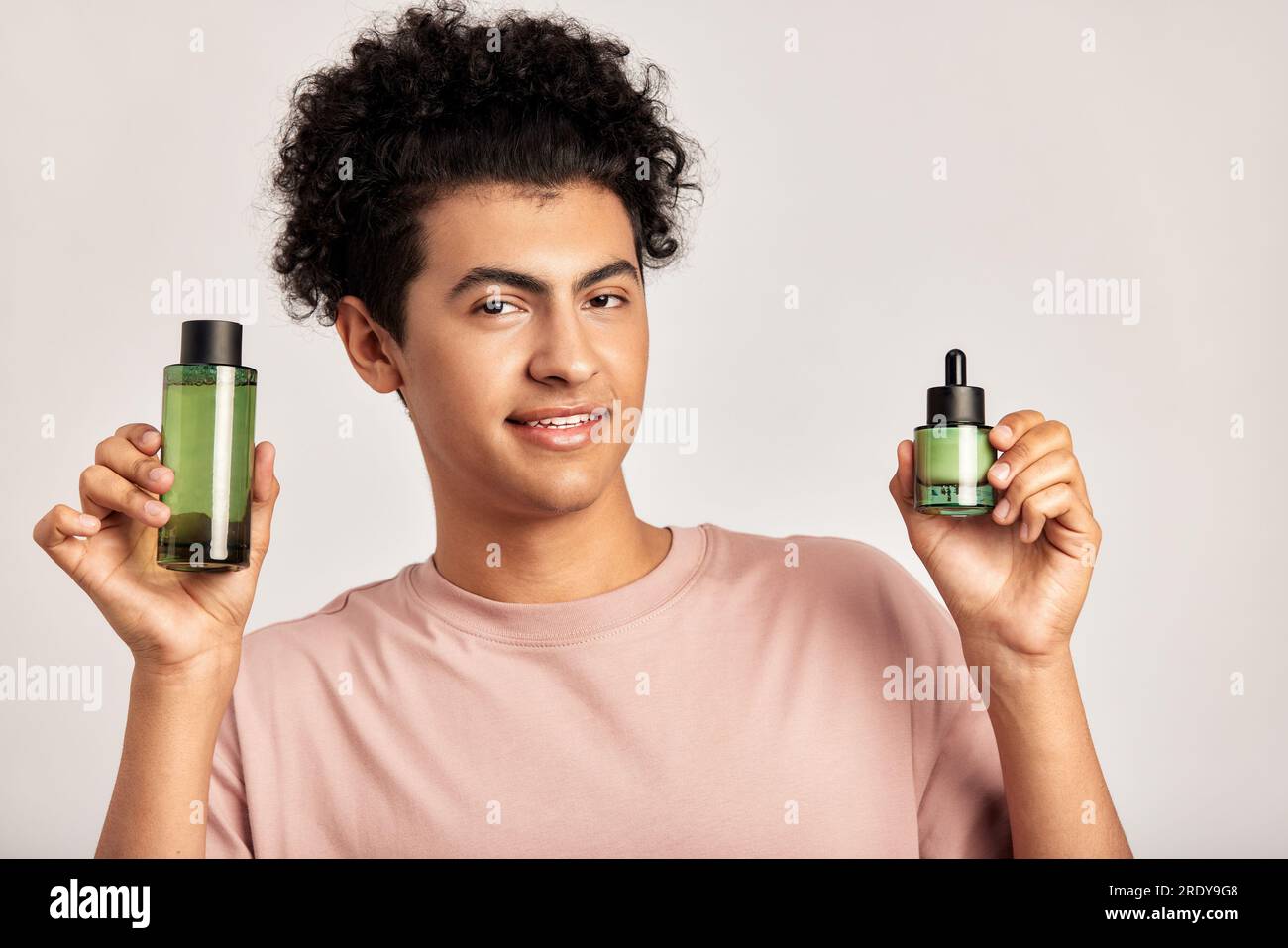 Studio portrait of young handsome smiling guy with bottles of ...