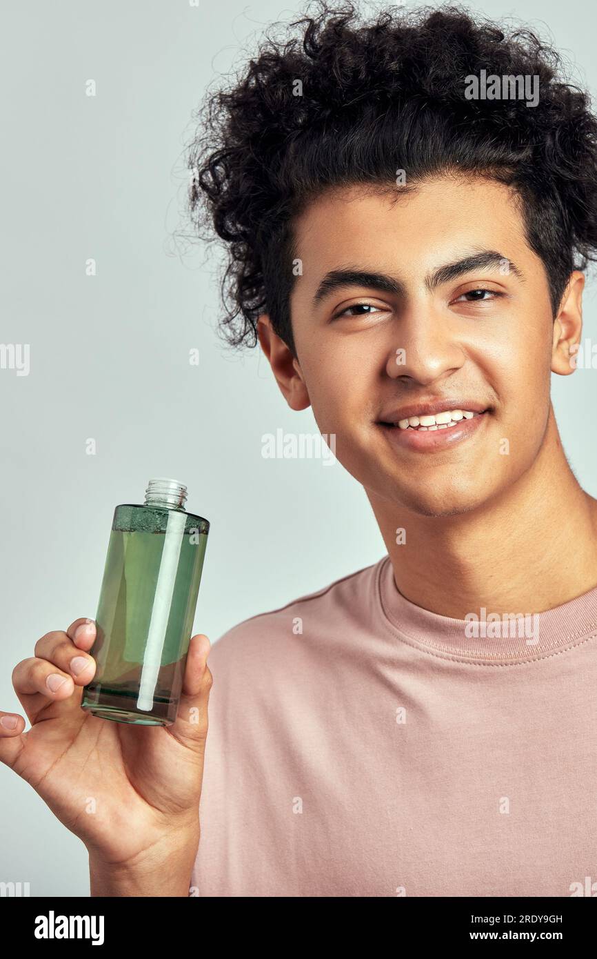 Studio close up portrait of a young handsome smiling guy with a bottle ...