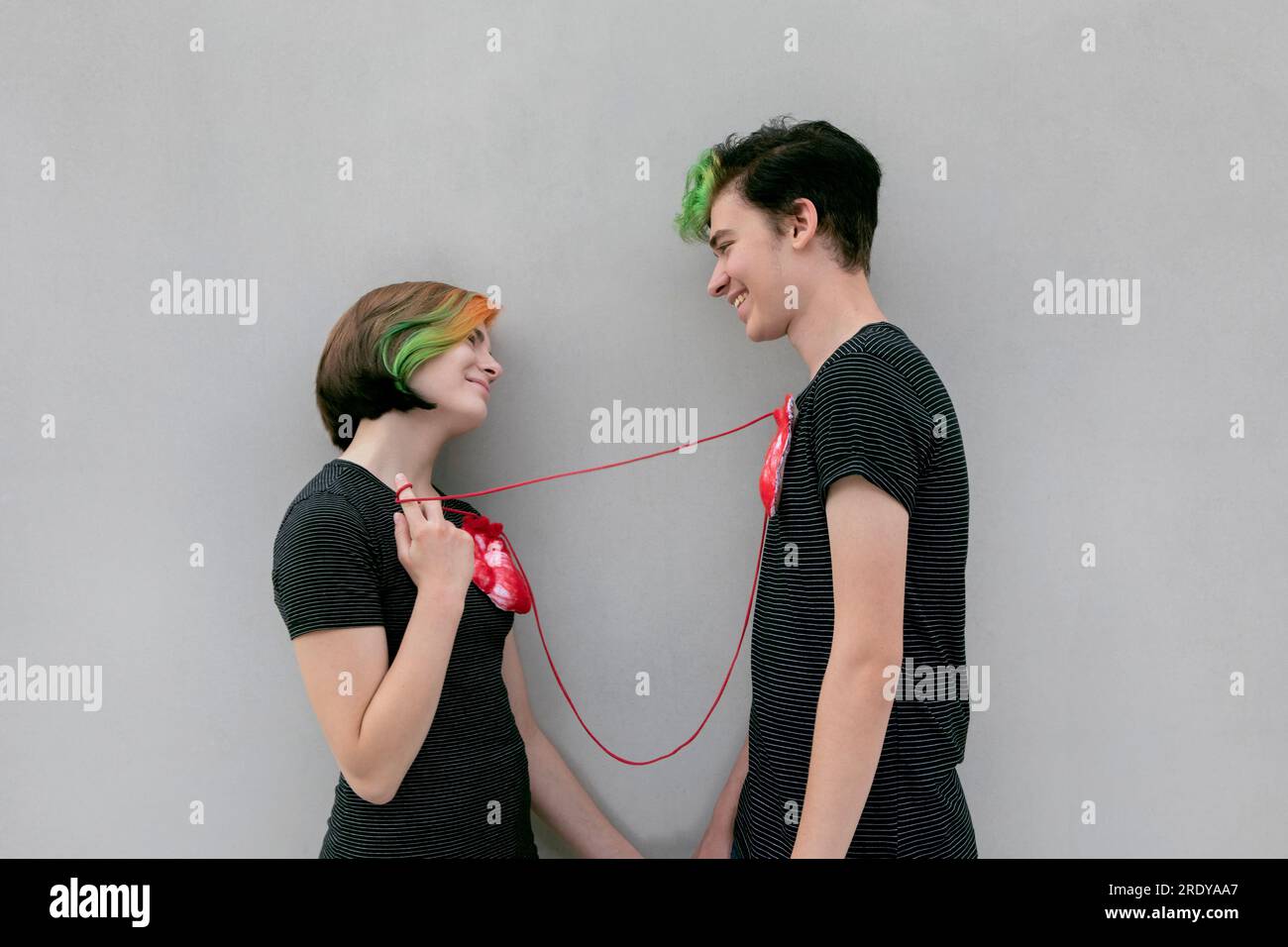 Teenage couple connected hearts with rope against gray background Stock ...