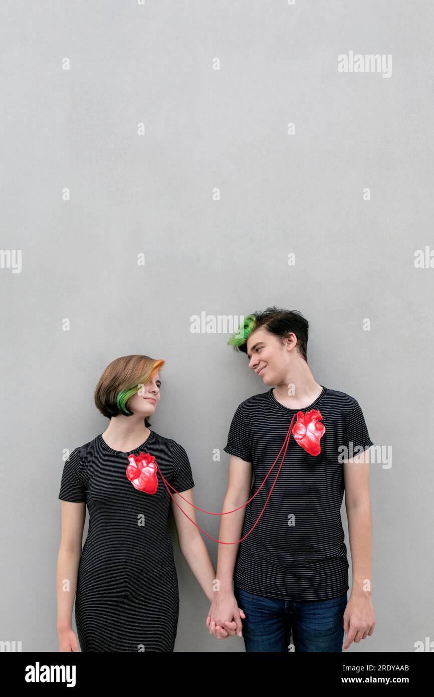 Teenage couple connected with hearts against gray background Stock ...