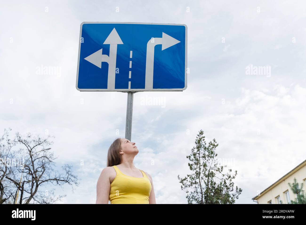 Woman standing under directional sign board Stock Photo - Alamy