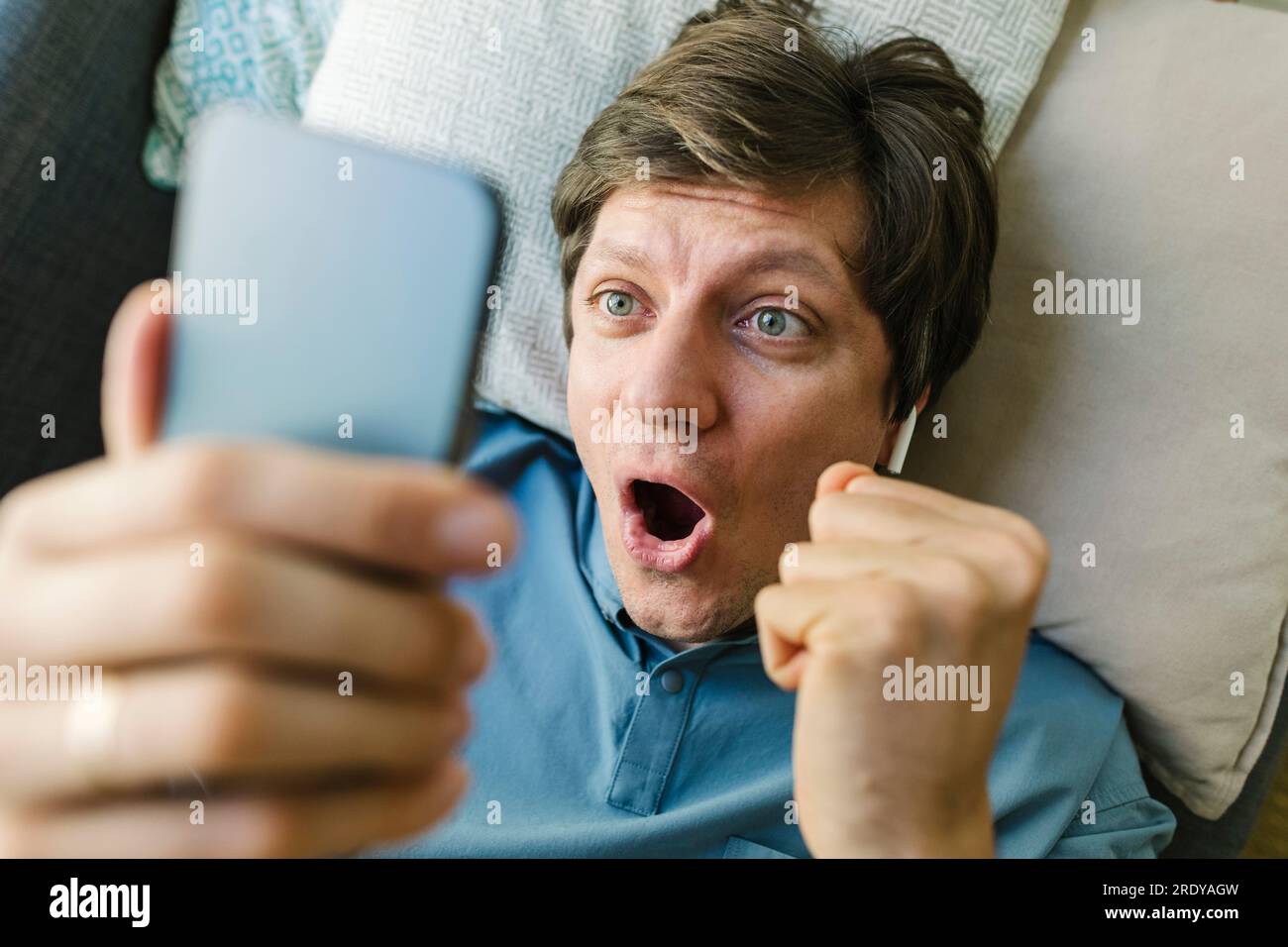 Excited man holding smartphone hi-res stock photography and images - Alamy