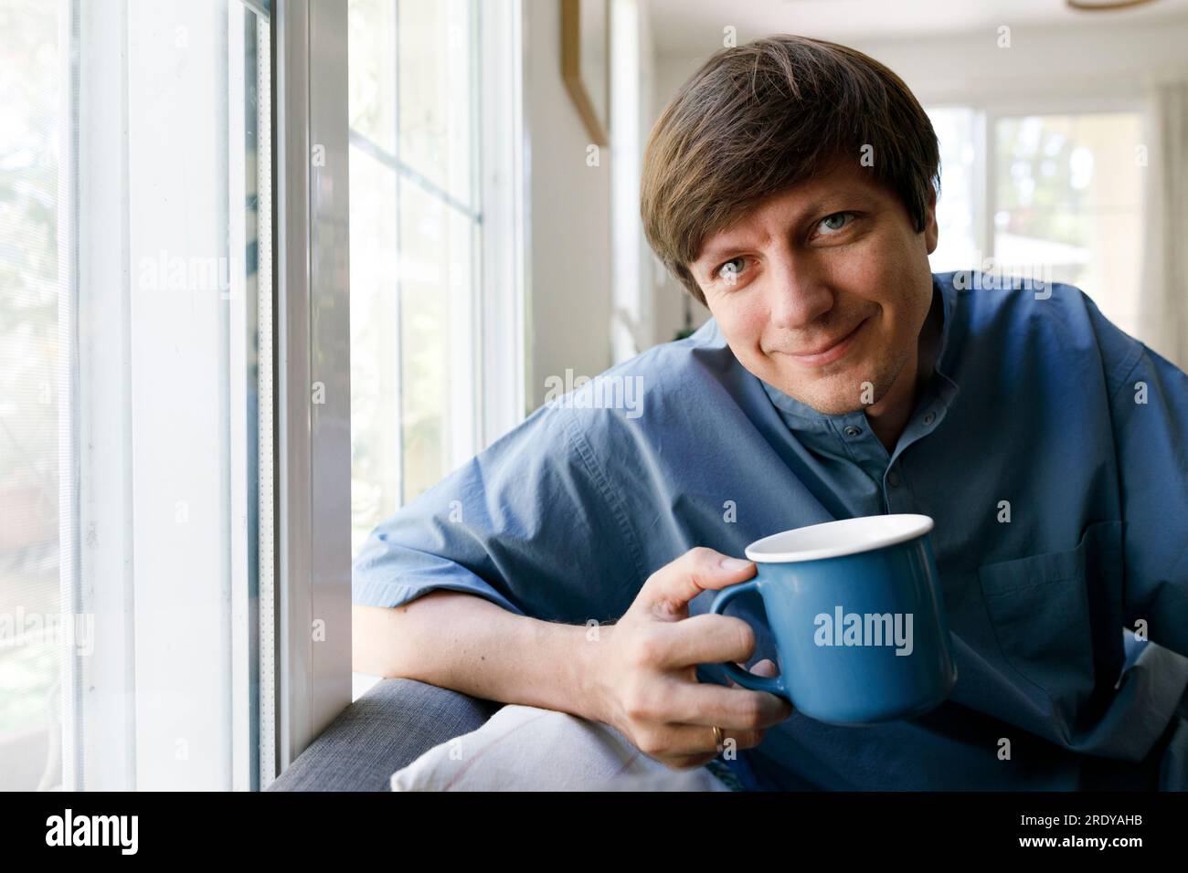 Smiling man drinking tea in living room Stock Photo - Alamy