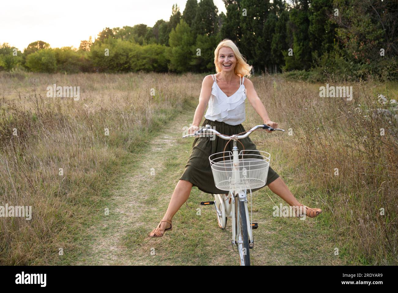 Happy mature woman riding bicycle on field Stock Photo - Alamy