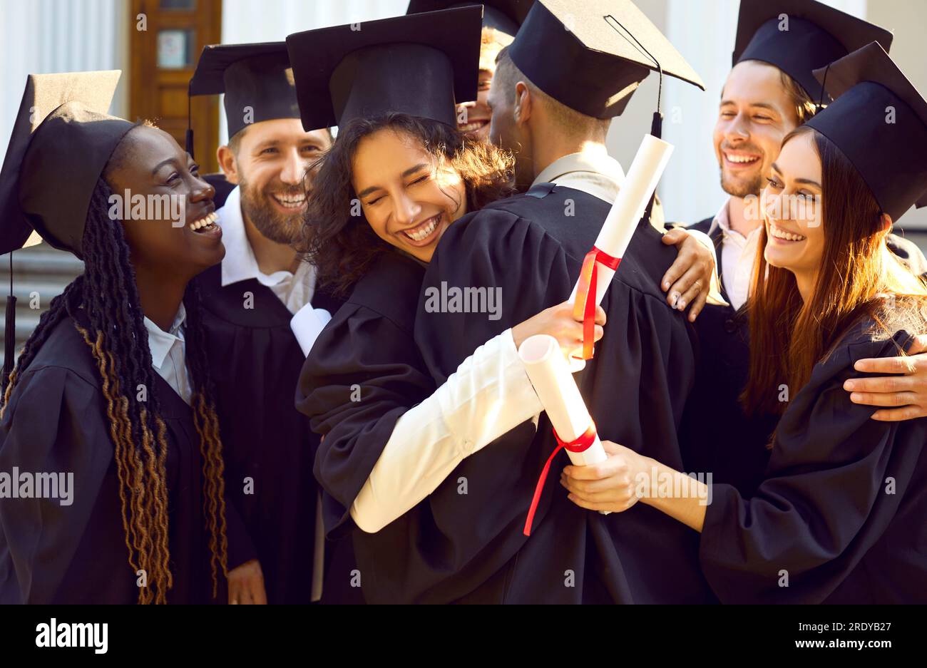 Excited students hugging each other after receiving diplomas at ...