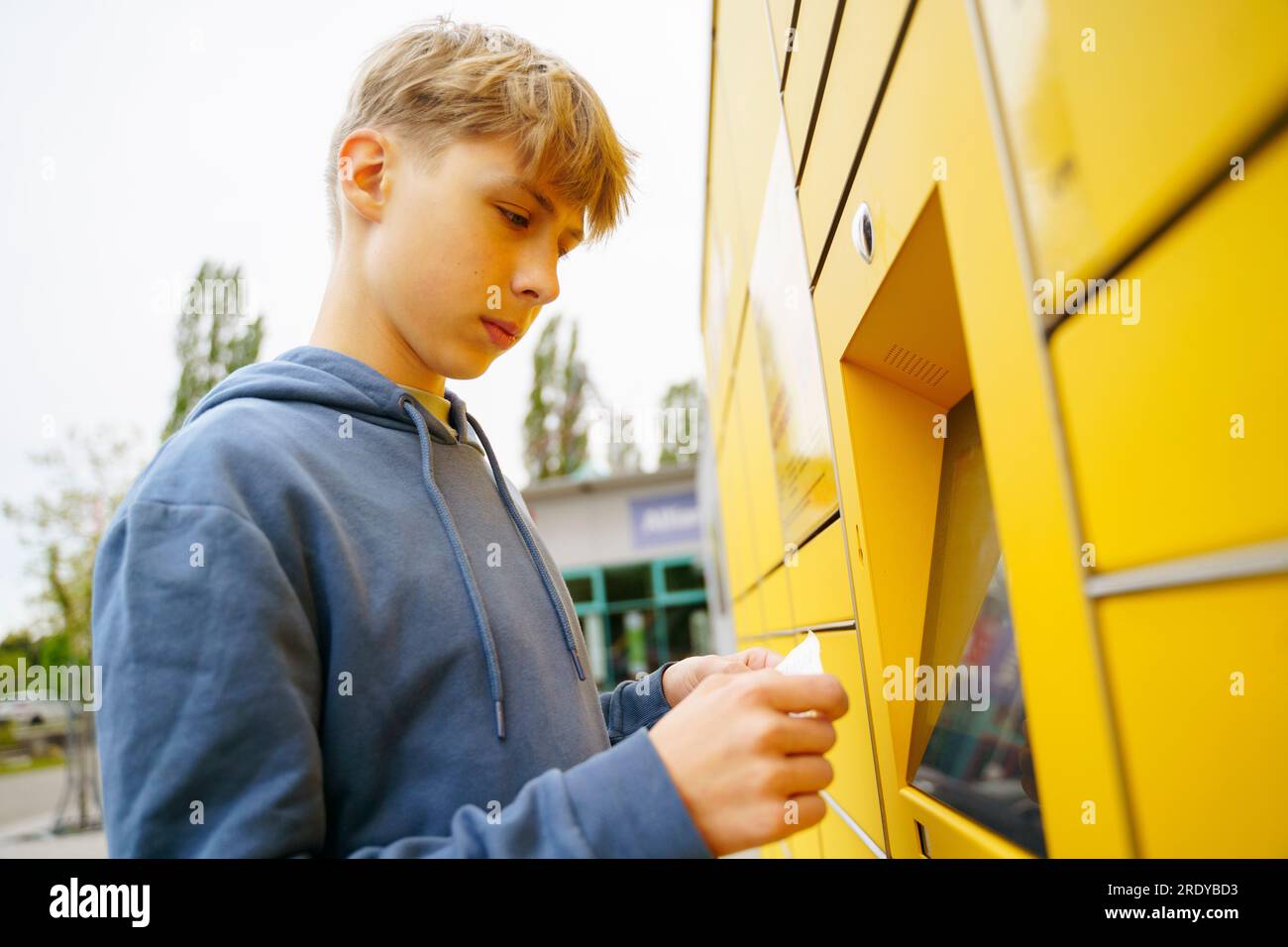 Boy with ticket standing in front of yellow parcel locker Stock Photo ...