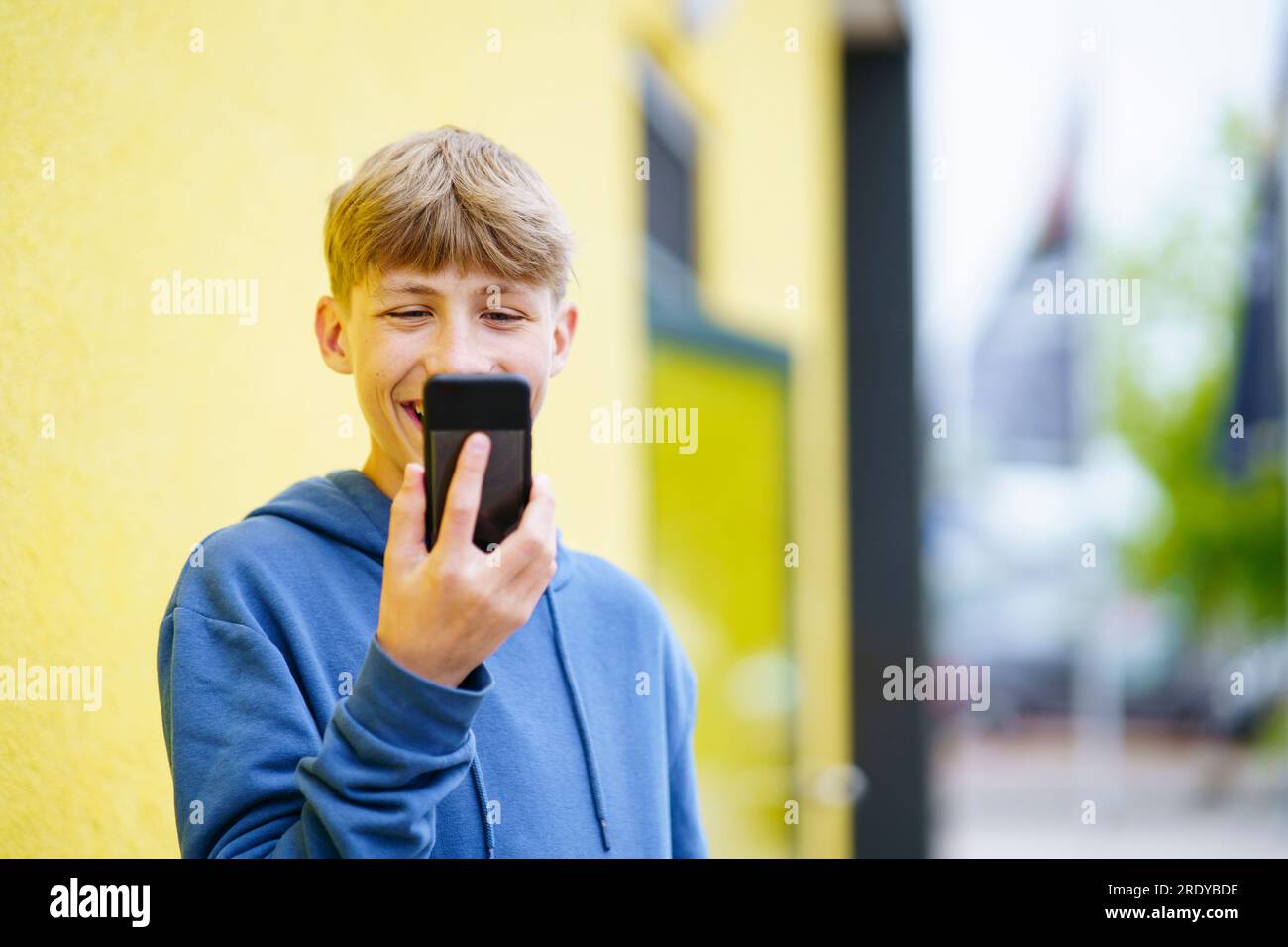 Happy blond boy talking on video call in front of yellow wall Stock ...