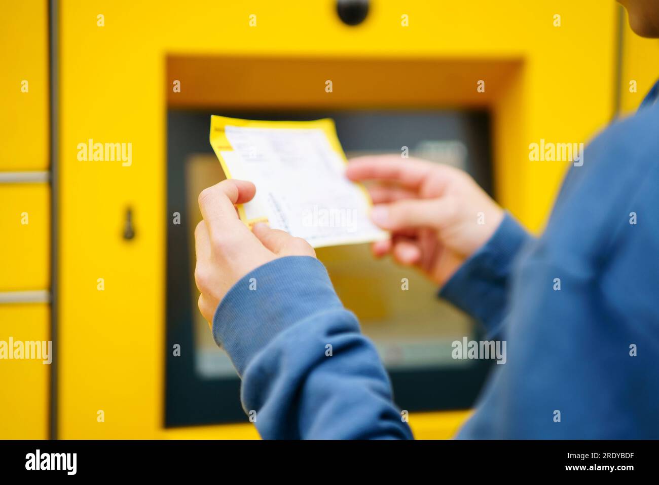 Boy holding ticket in front of parcel locker Stock Photo - Alamy