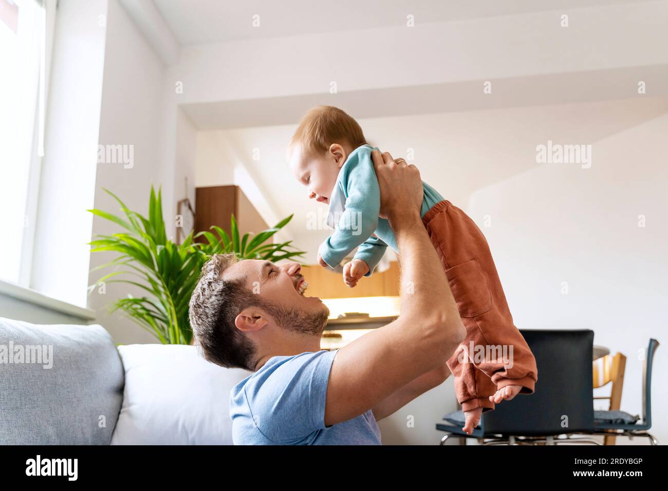 Father lifting cute baby boy in living room at home Stock Photo - Alamy