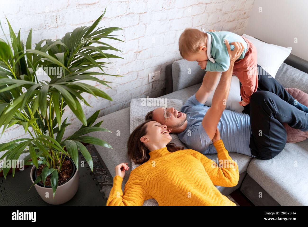 Happy parents spending leisure time with baby boy on couch at home ...