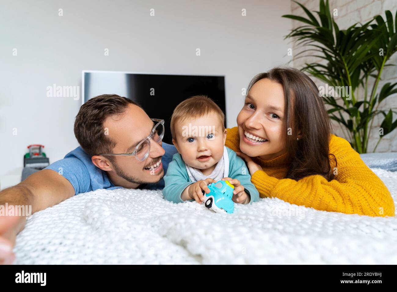 Cute baby boy with parents lying on couch at home Stock Photo - Alamy
