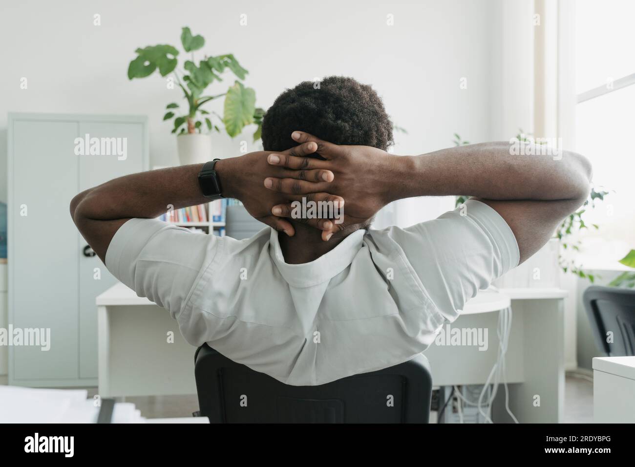 Businessman resting with hands behind head at office desk Stock Photo ...