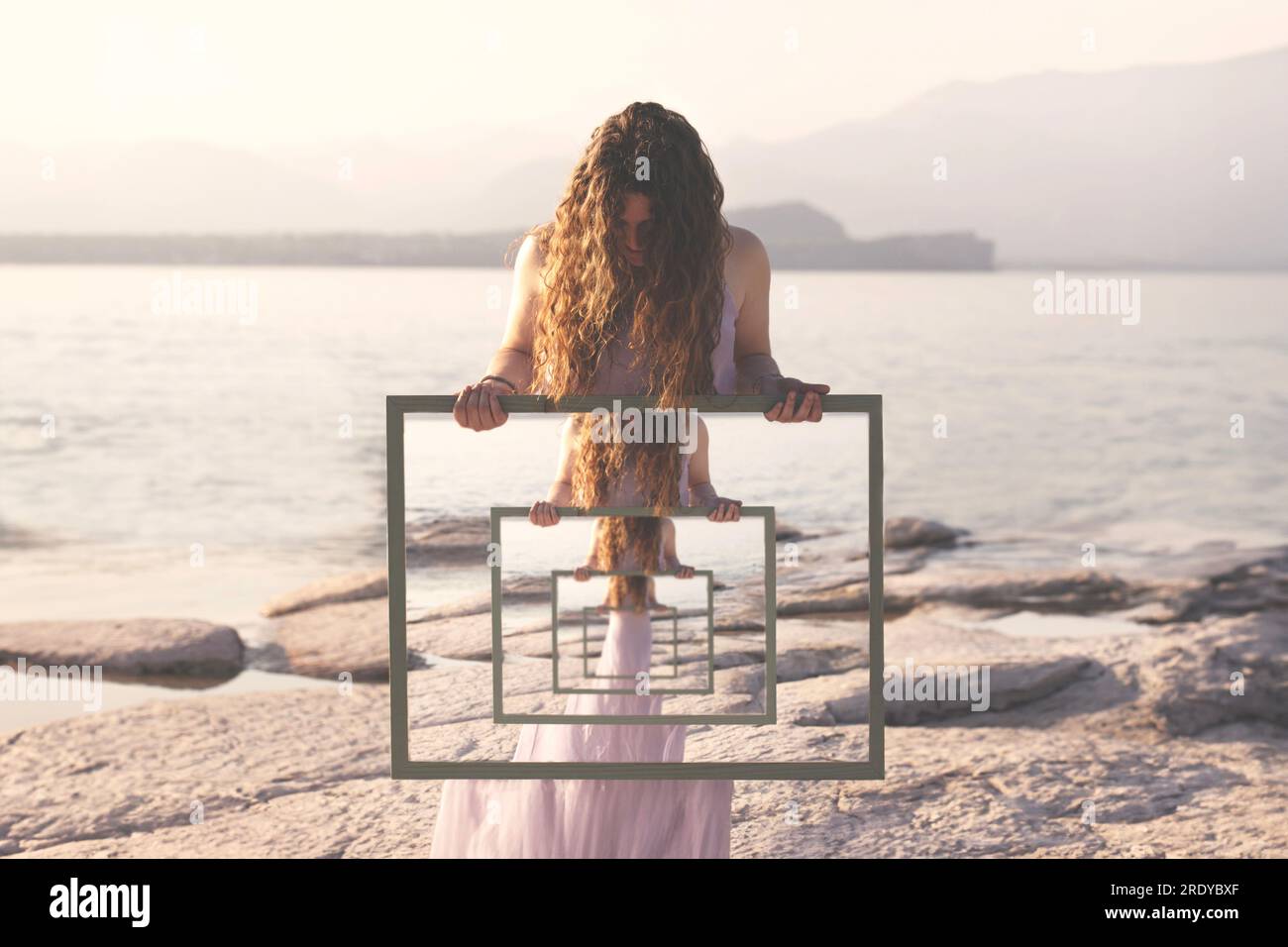 woman holding a surreal frame with the reflection of herself in loops ...