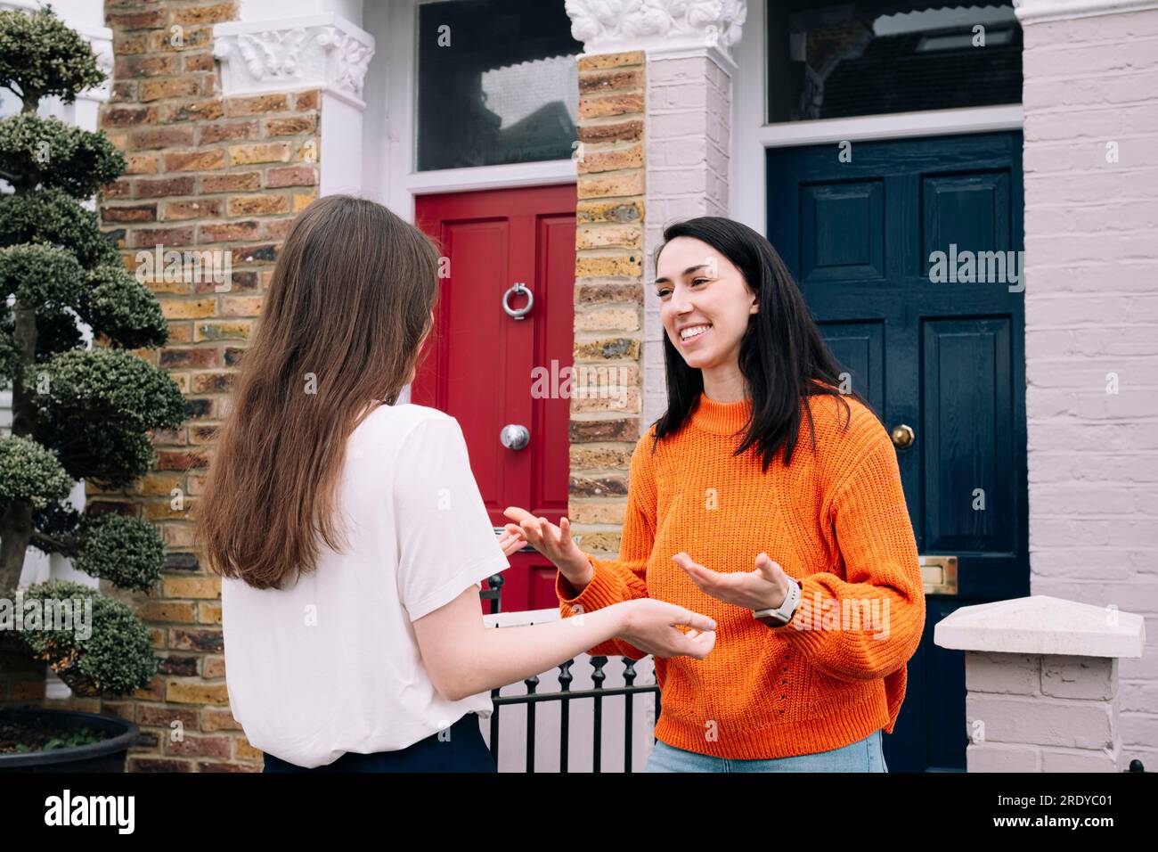 Smiling friends talking and gesturing in front of house Stock Photo - Alamy