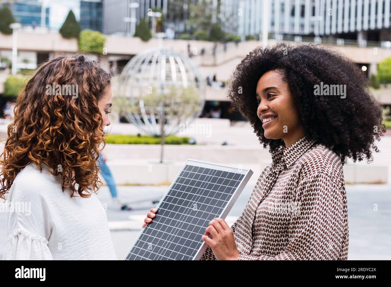 Happy businesswoman showing solar panel to colleague in office park ...