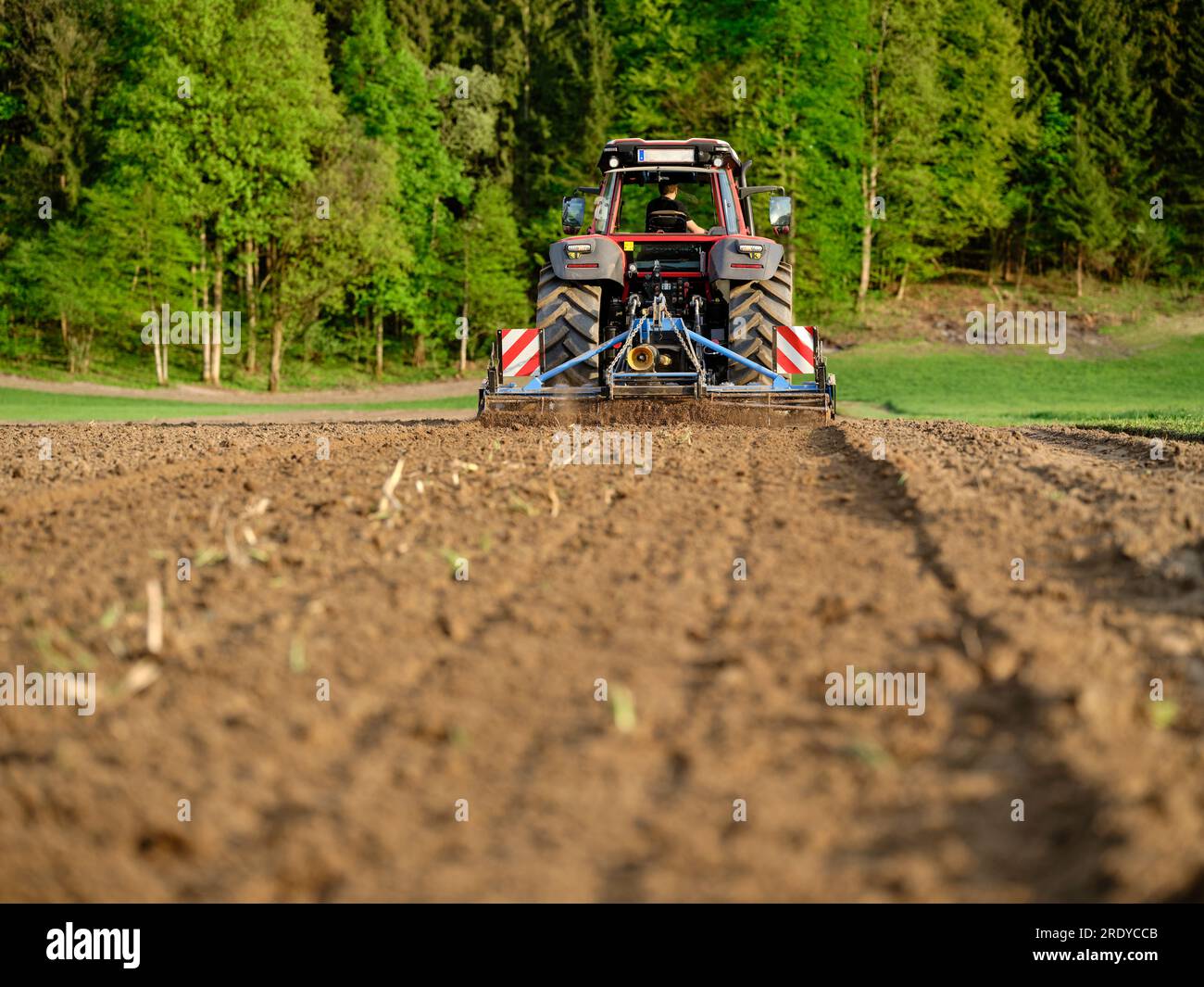 Farmer leveling soil using tractor in farm at sunrise Stock Photo - Alamy