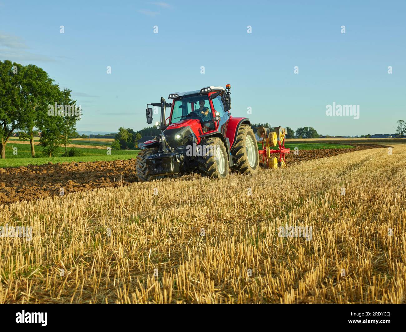 Farmer using tractor and plowing land near dry grass at sunrise Stock ...