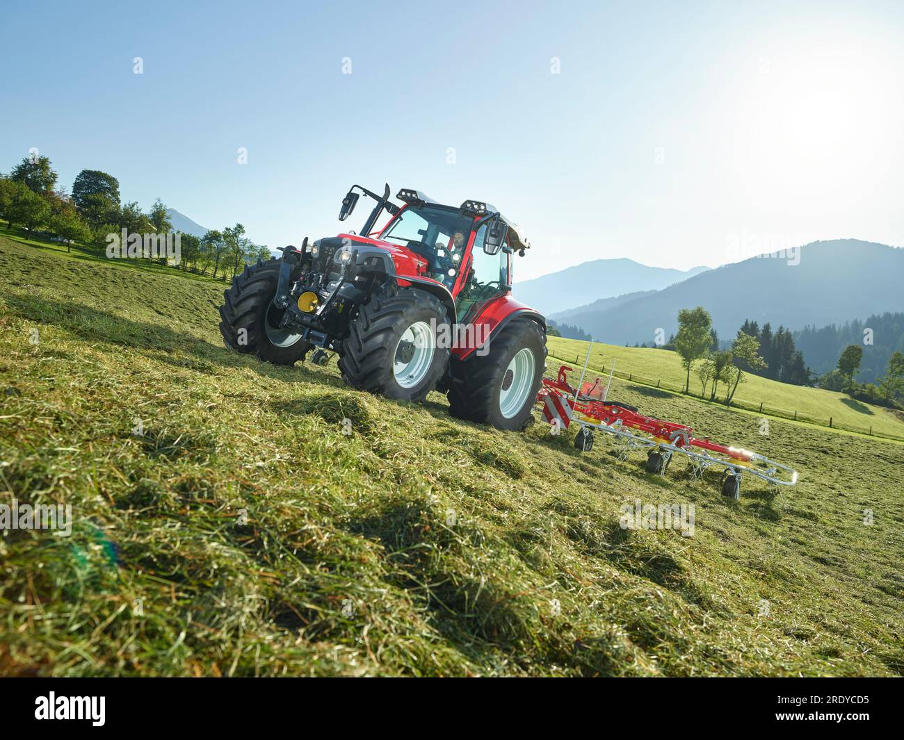 Farmer using tractor and mowing grass field near mountain Stock Photo ...