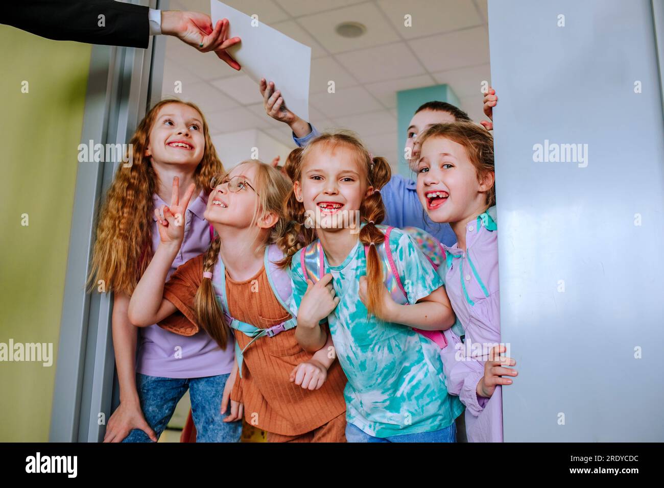 Hand of teacher giving report card to school children standing in ...
