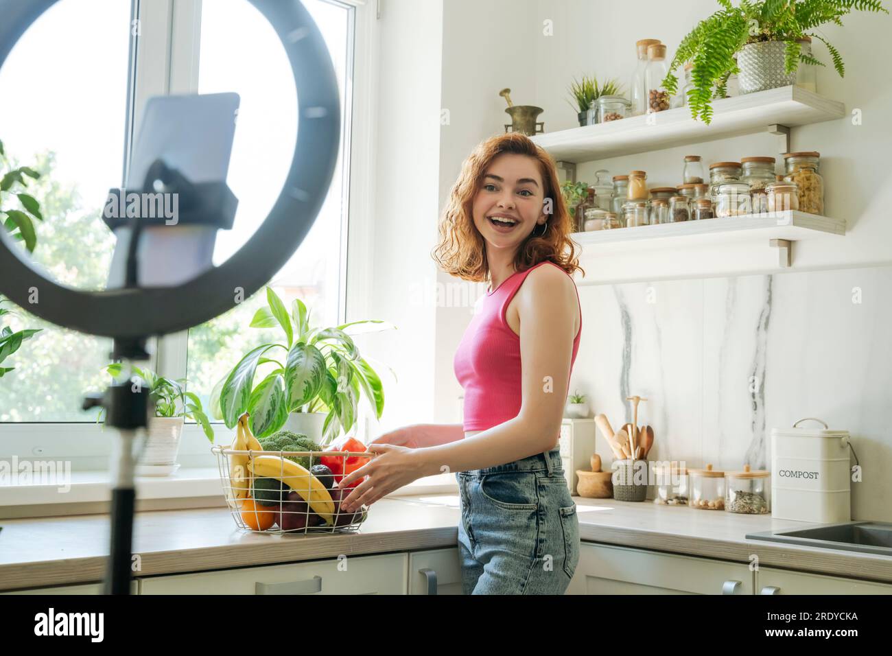 Happy influencer with basket of fruits and vegetables standing by ...
