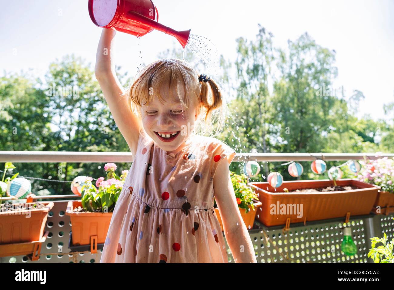 Happy girl pouring water on herself in balcony Stock Photo - Alamy
