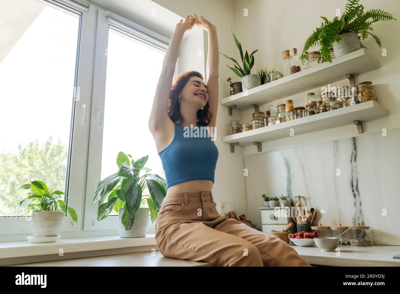 Happy woman stretching arms on kitchen counter at home Stock Photo - Alamy