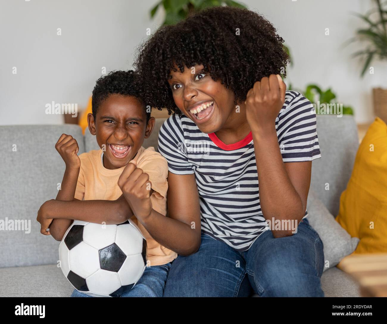 Happy mother and son cheering and sitting on sofa at home Stock Photo ...