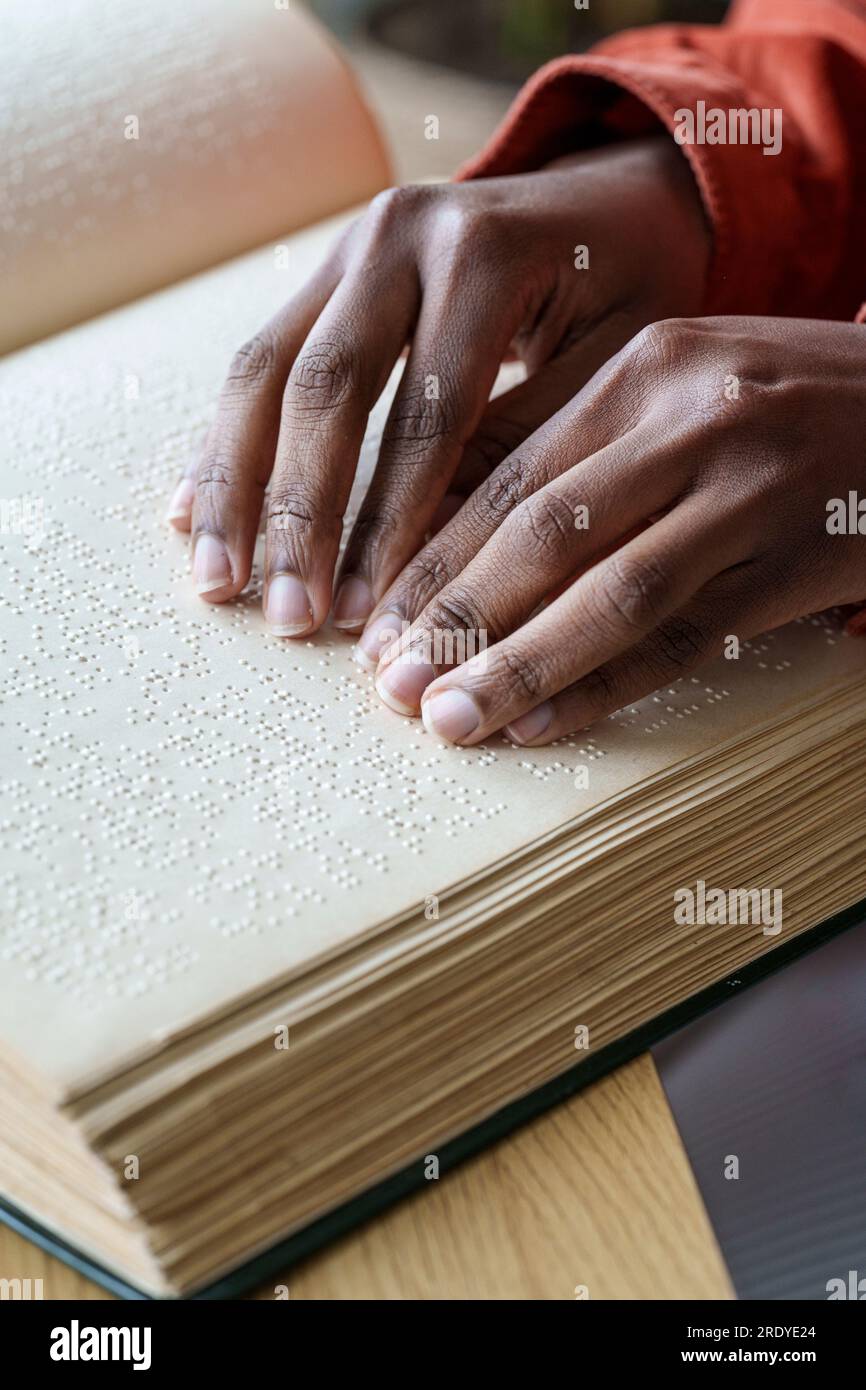 Hands of woman reading braille text from book on table Stock Photo - Alamy