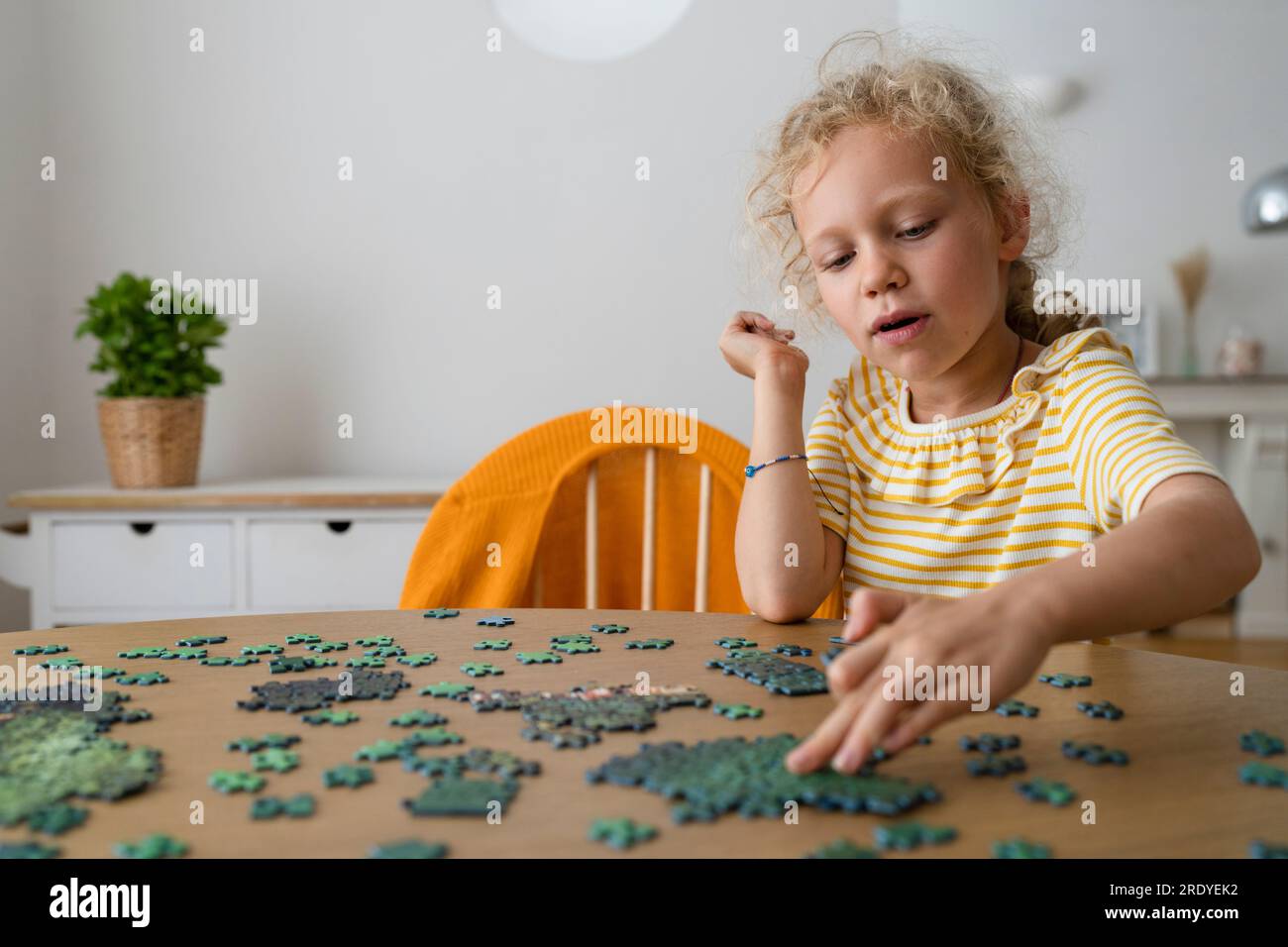 Girl solving jigsaw puzzle at home Stock Photo - Alamy